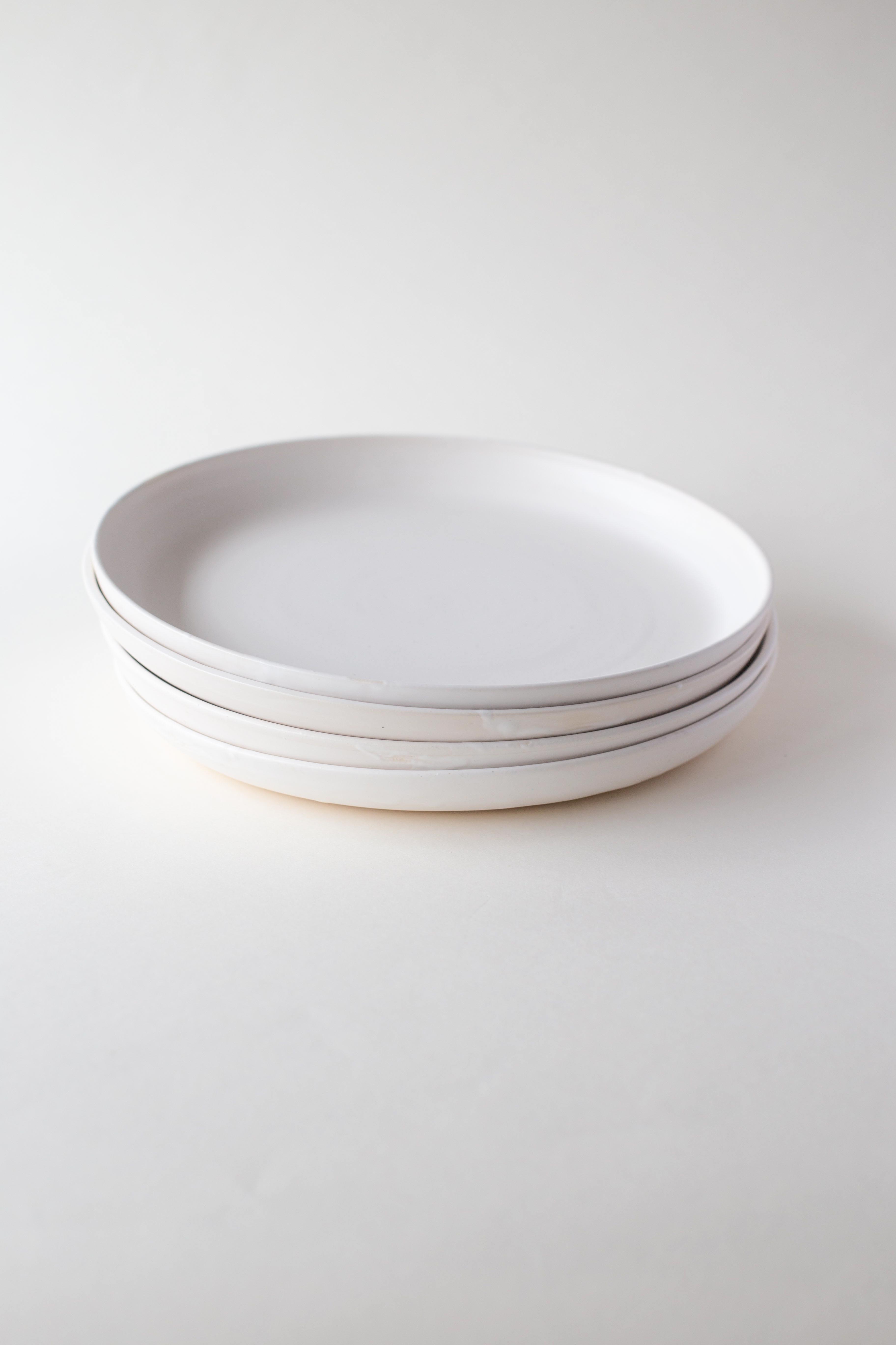 A handthrown and unique ceramic dinner plate in an off-white glaze ...