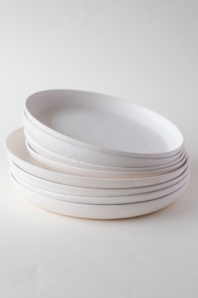 A handthrown and unique ceramic dinner plate in an off-white glaze ...